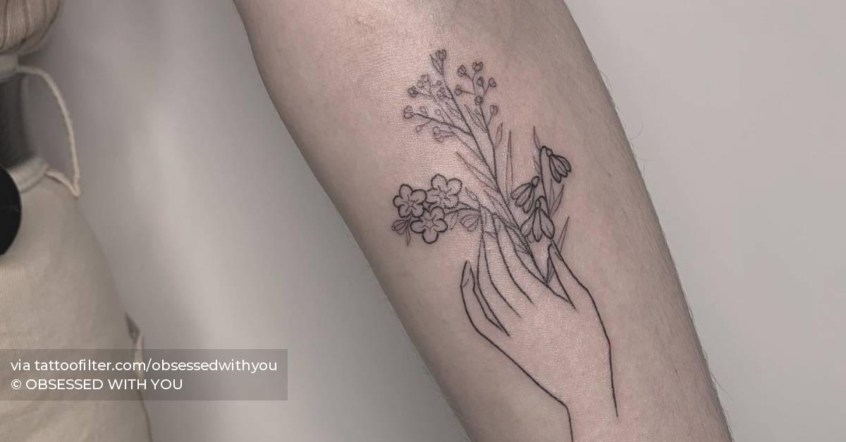 Hand holding flowers tattooed on the inner forearm.