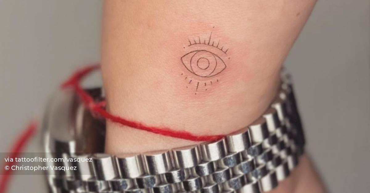 Fine line evil eye tattoo located on the wrist.