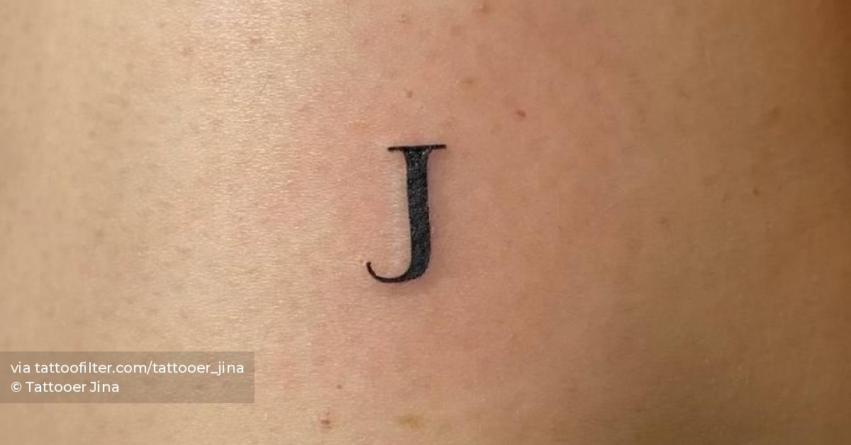 Minimalistic letter "J" tattoo located on the tricep.