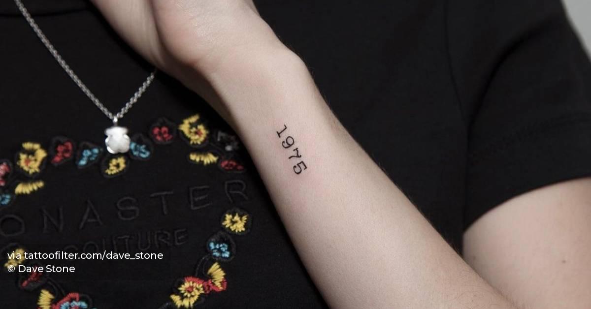 "1975" lettering tattoo on the wrist.