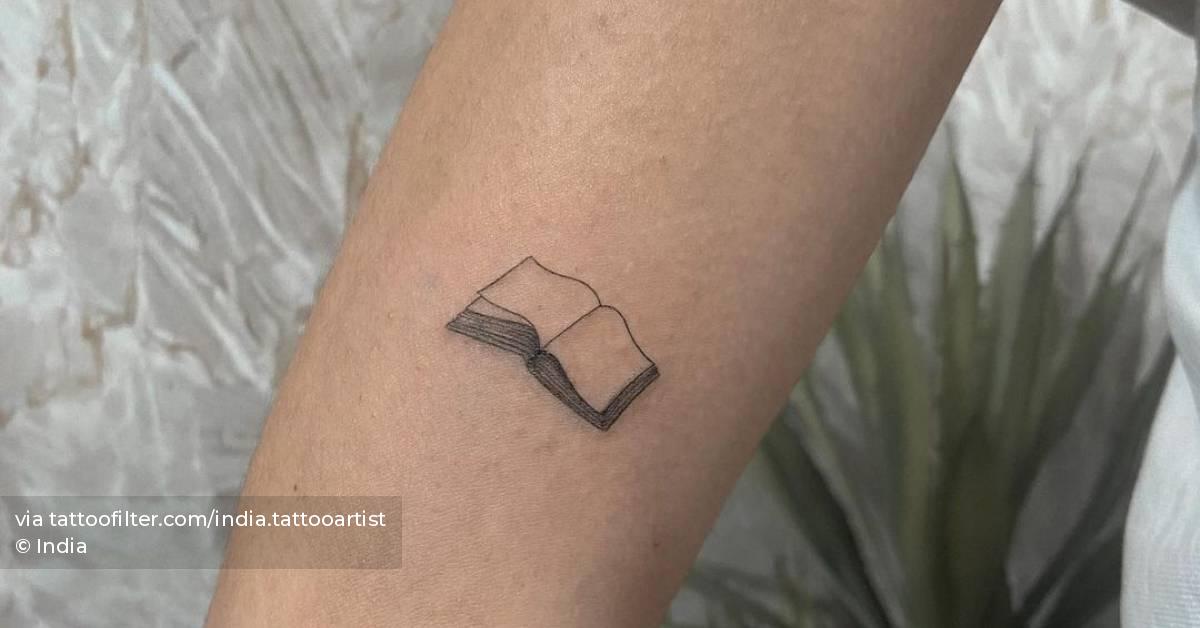 Fine line book tattoo on the upper arm.