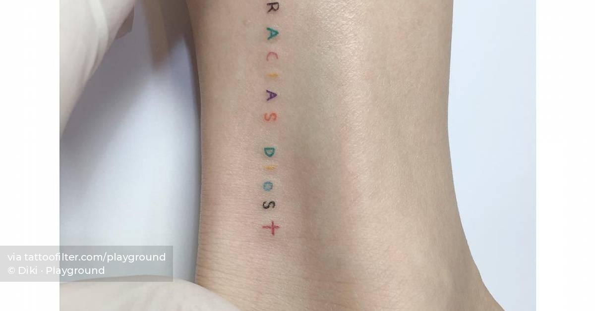 Colorful "Gracias Dios" lettering tattoo located on the