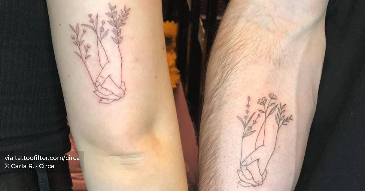 Holding hands matching tattoos for couple.