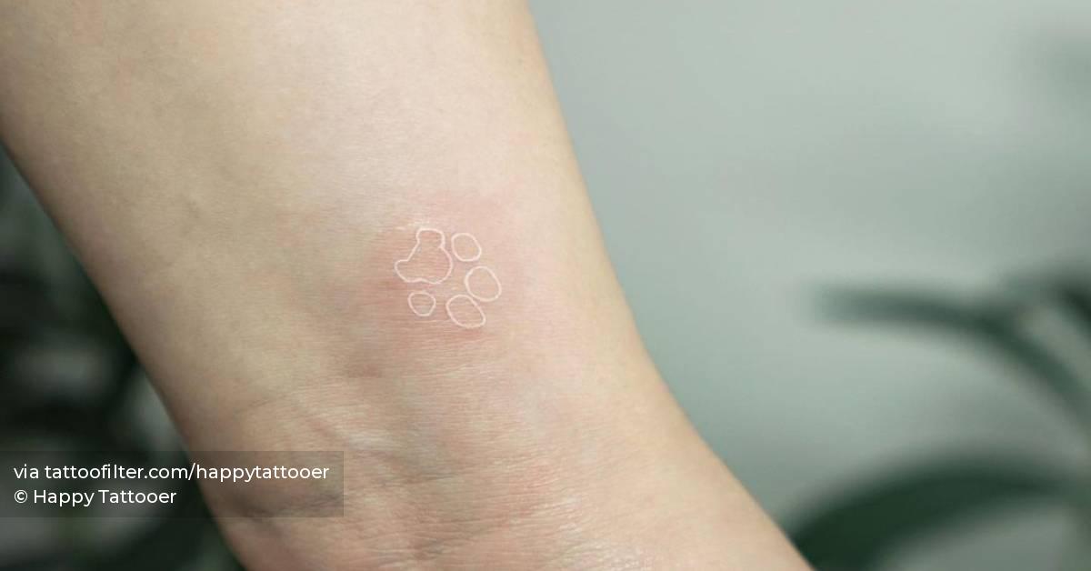 Fine line dog paw tattoo done in white ink.