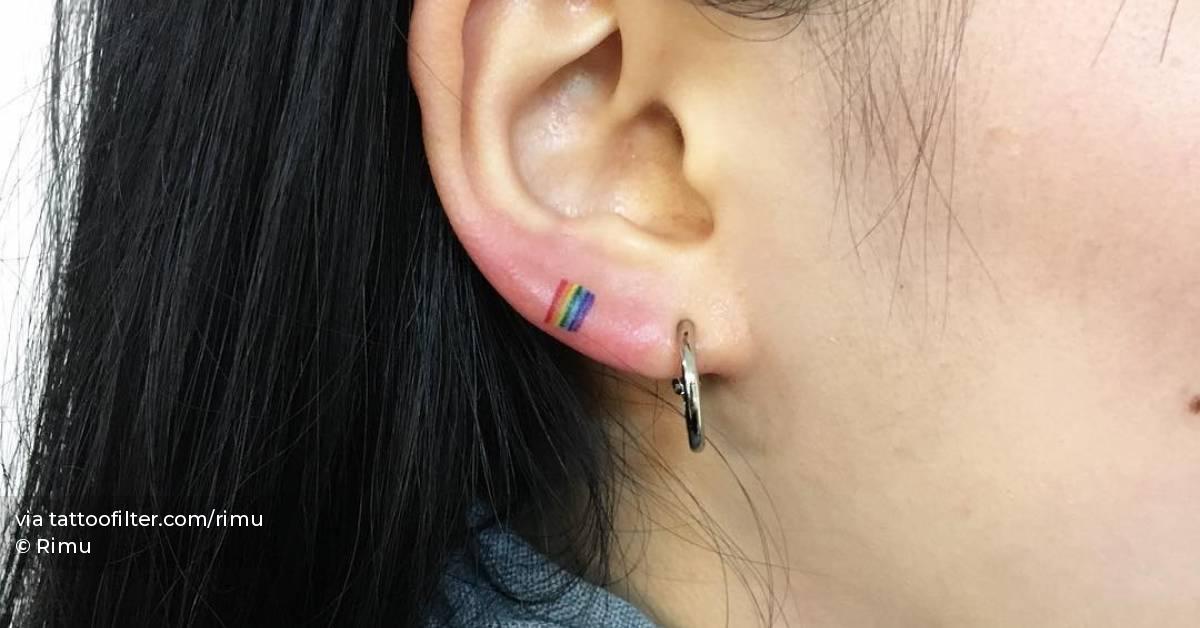 Tiny minimalistic rainbow tattoo done on the earlobe.