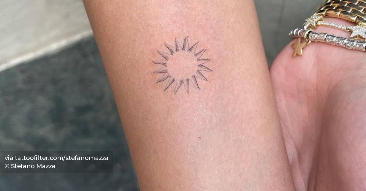 Fine line sun tattoo on the inner forearm.