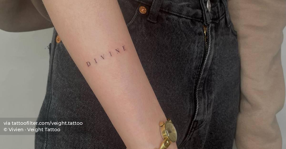 Word "divine" tattooed on the forearm.