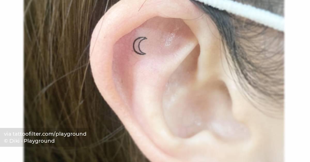 Tiny crescent moon tattoo placed on the ear.