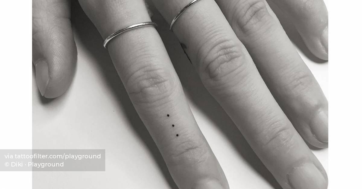 Minimalistic dots tattooed on the finger.