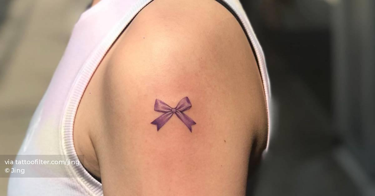 Micro-realistic purple ribbon tattooed on the shoulder.