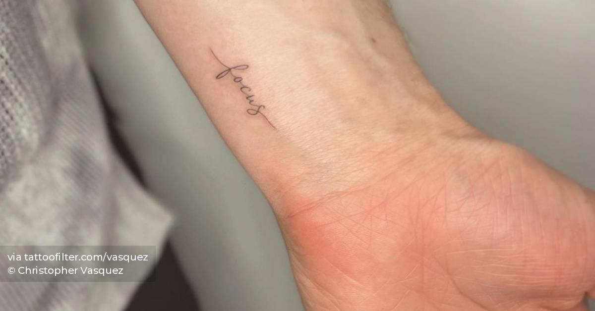 "Focus" lettering tattoo located on the wrist.