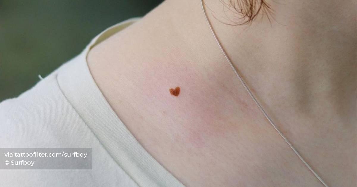 Micro red heart tattoo located on the collarbone.