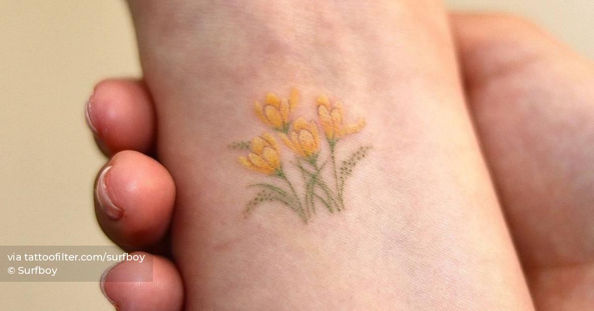 Hand poked saffron tattoo located on the wrist.