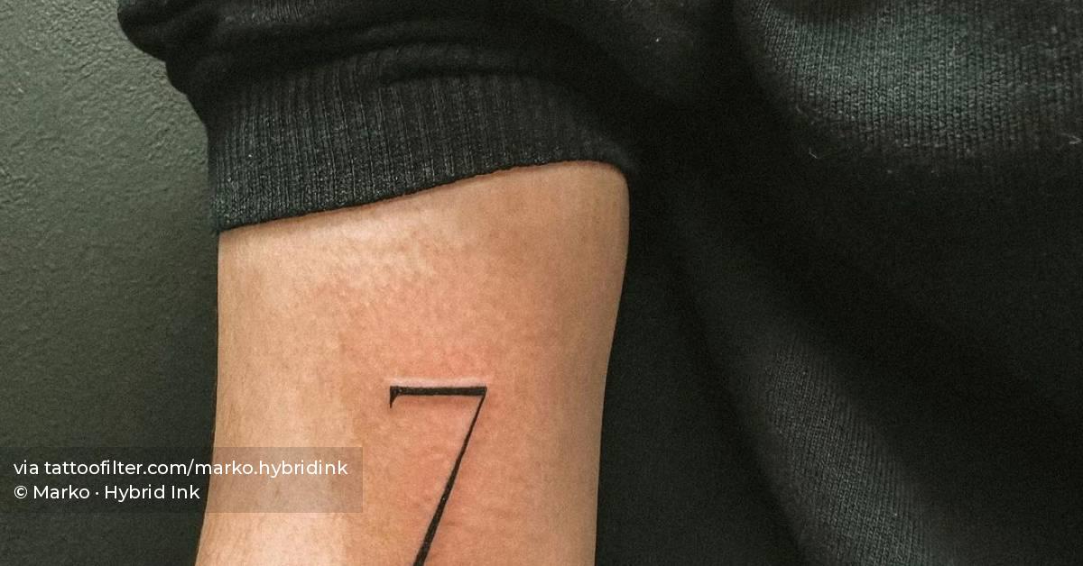 Minimalistic number "7" tattoo located on the bicep.