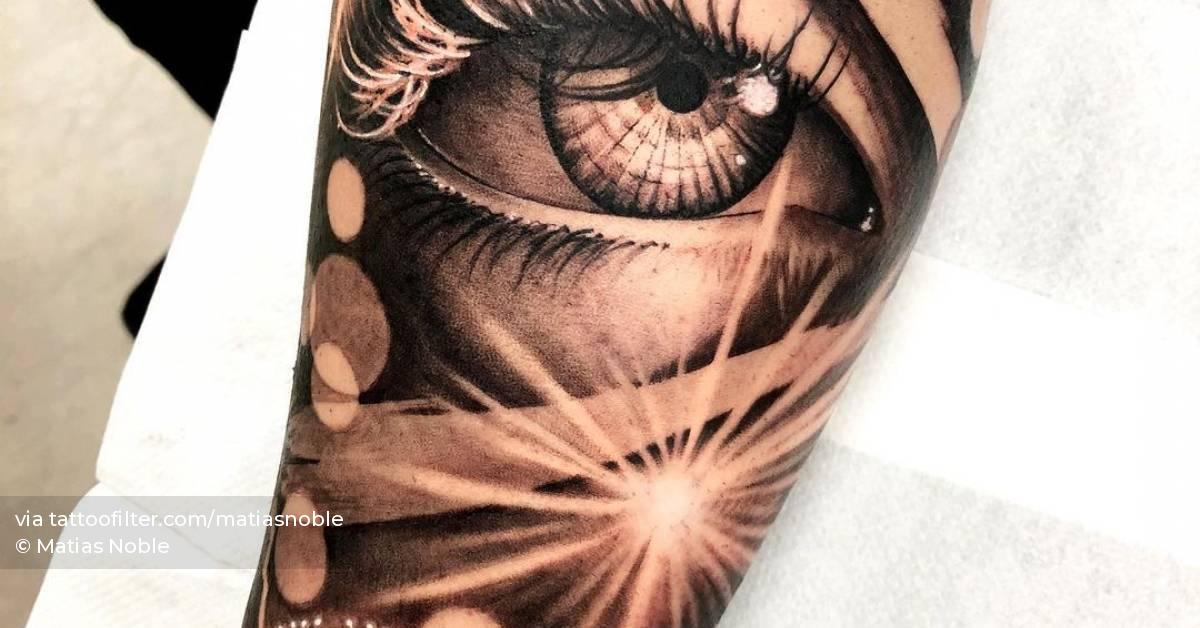 Black and grey eye and tree tattoo located on the
