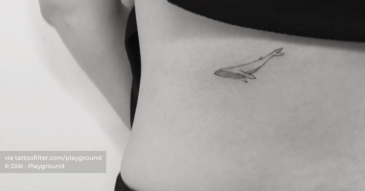 Fine line whale tattoo located on the lower back.