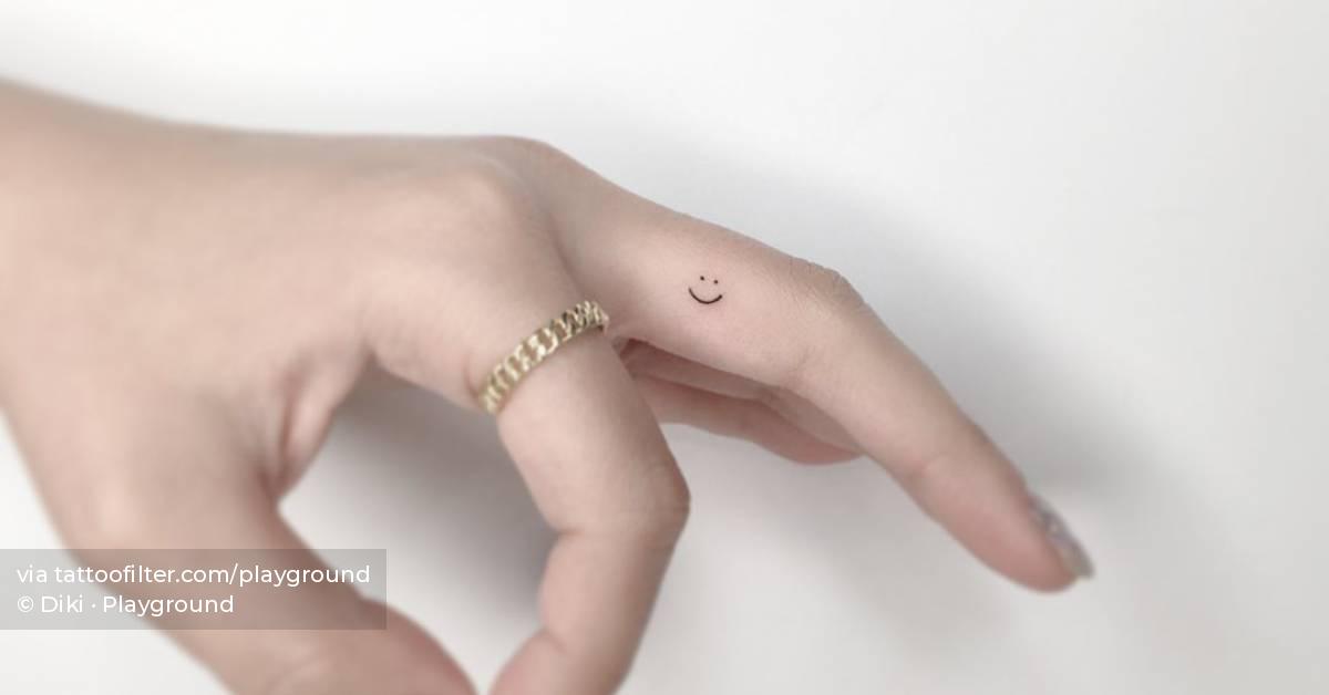 Super tiny smiley face tattoo placed on the finger.