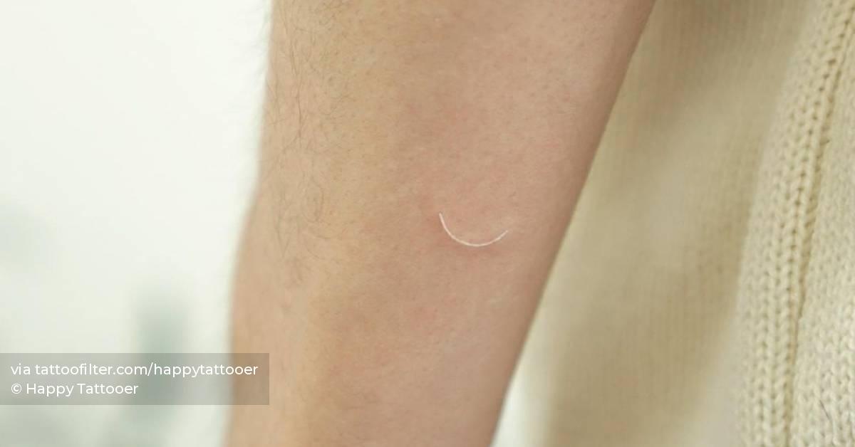Minimalistic line in white ink tattooed on the forearm.