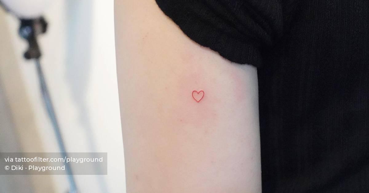 Minimalistic little red heart tattoo located on the