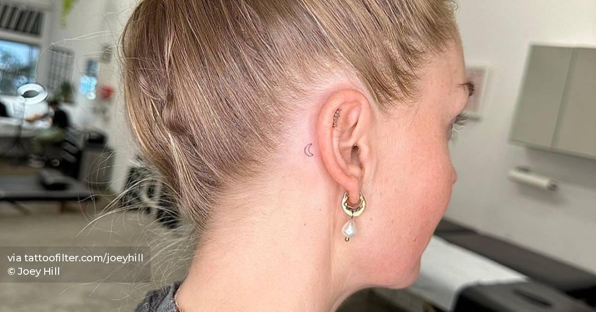 Fine line crescent moon tattoo located behind the ear.