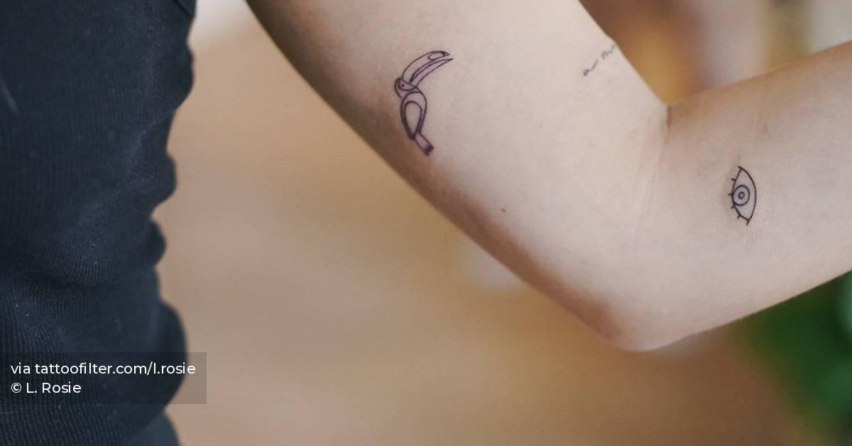 Fine line toucan and evil eye tattoos.