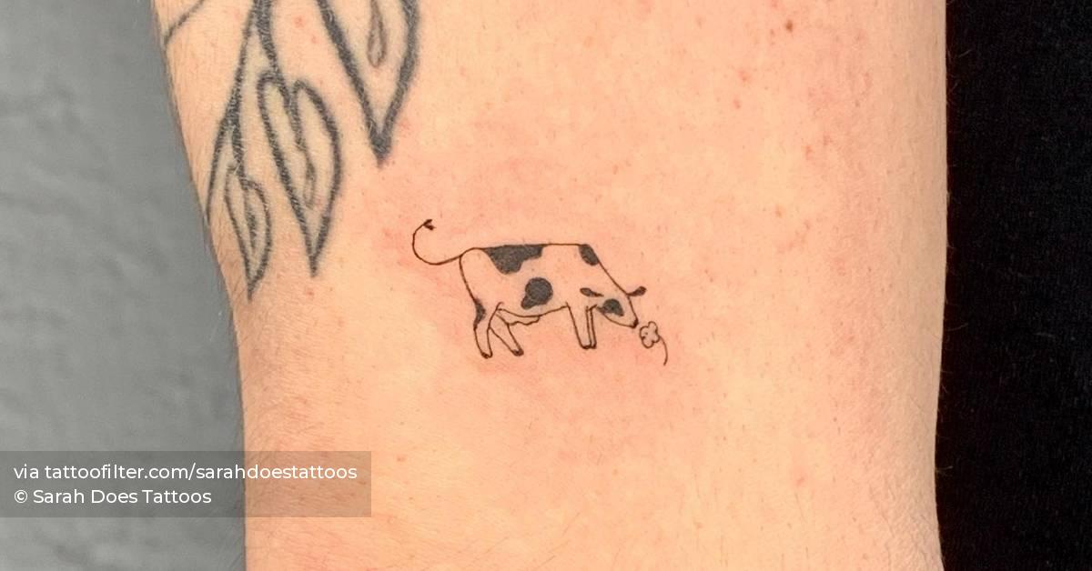 Tiny cow tattoo located on the upper arm.