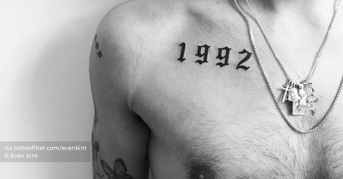 "1992" lettering tattoo done on the collarbone.