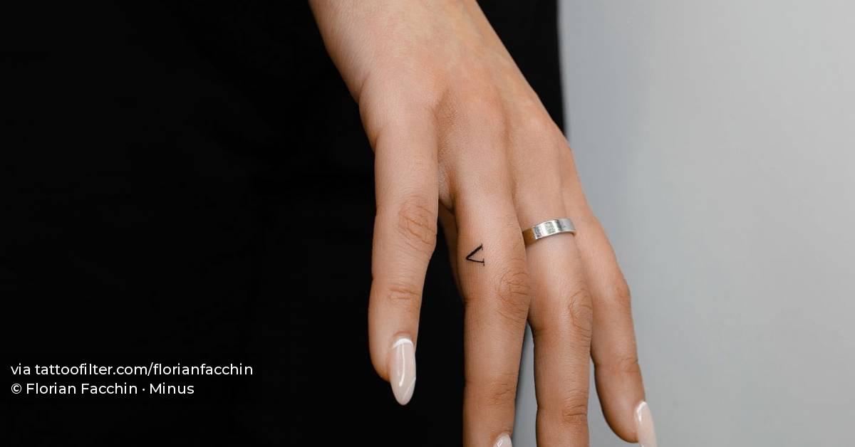 Minimalistic letter "V" tattoo located on the finger.