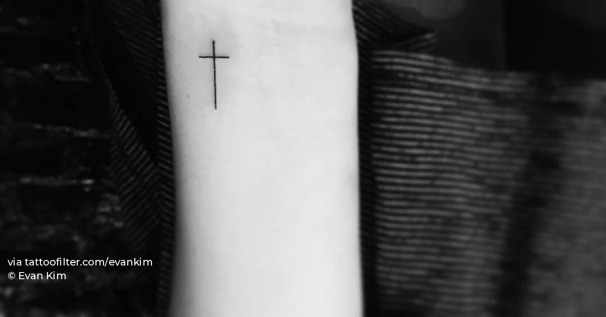 Minimalistic style cross tattoo located on the wrist.