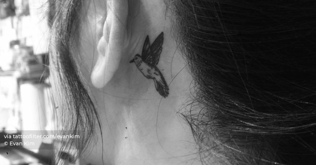 Tiny hummingbird tattoo placed behind the ear.