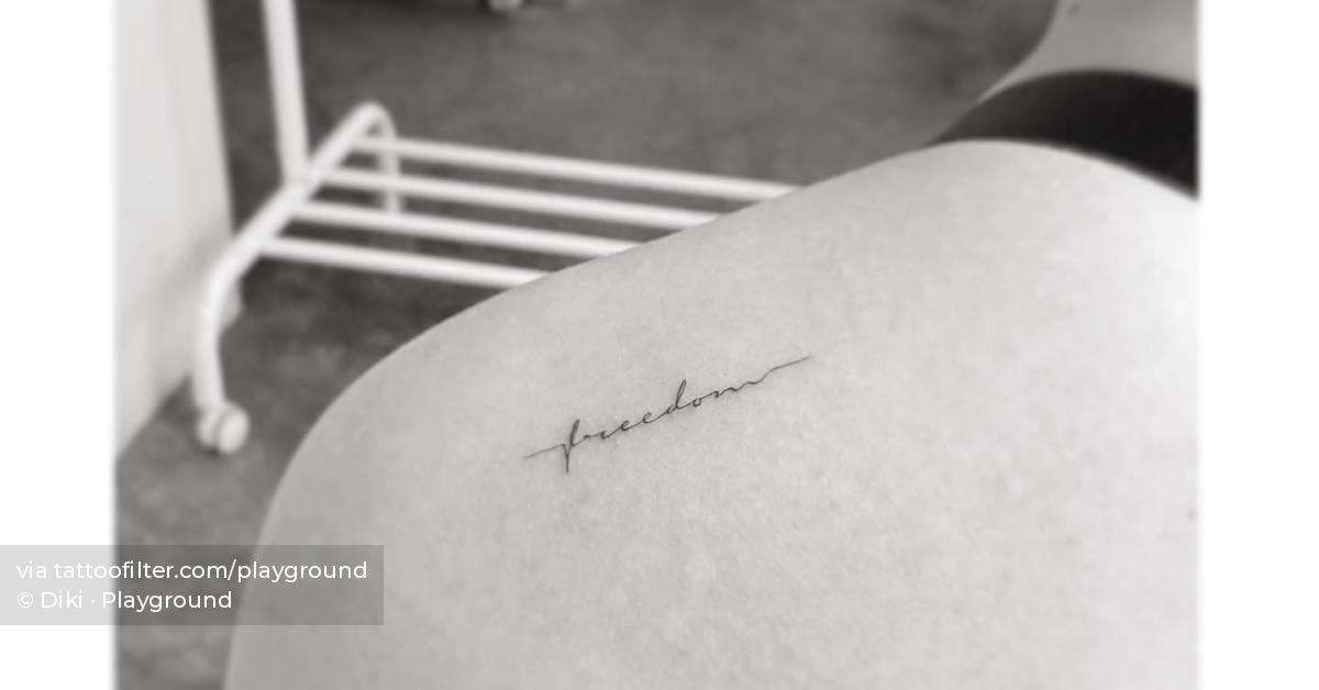 Tattoo of the word "freedom" handwritten on the top of