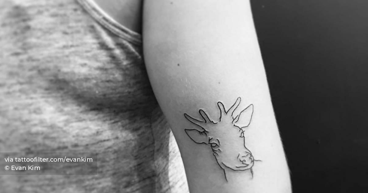 Fine line giraffe portrait tattooed on the tricep,