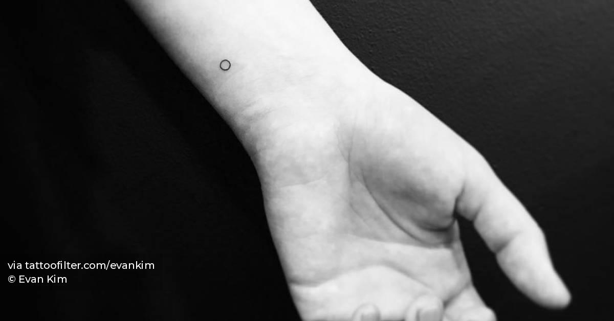 Tiny minimalistic circle tattoo located on the wrist.