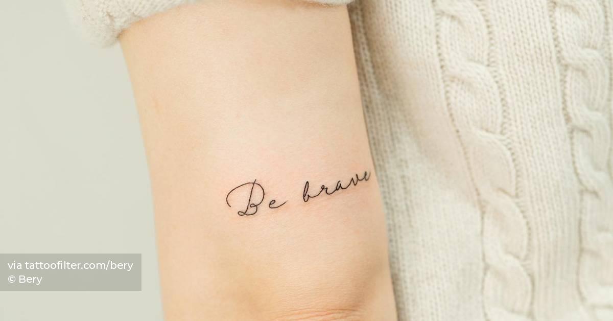 "Be brave" lettering tattoo located on the tricep.