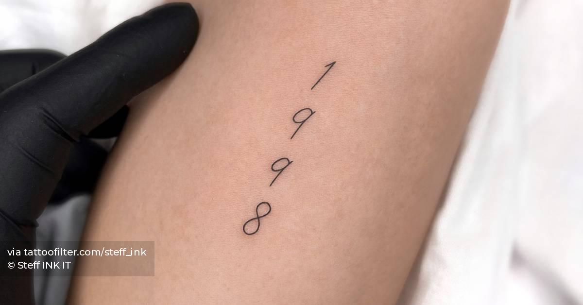 "1998" lettering tattoo placed on the inner forearm.