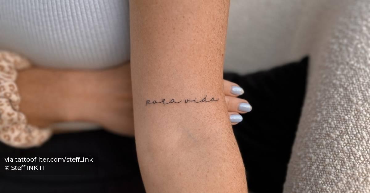 "Pura vida" lettering tattoo handwritten on the bicep.
