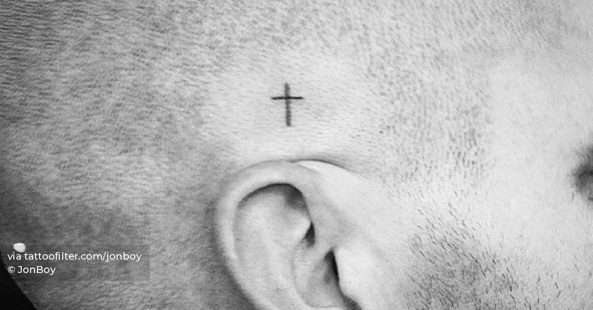 Minimalistic cross tattoo located on the head.