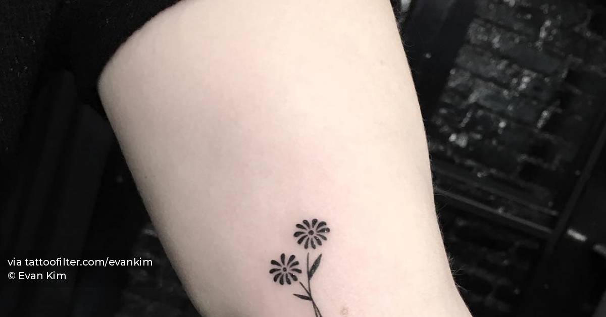 Minimalistic flower tattoo located on the inner arm.