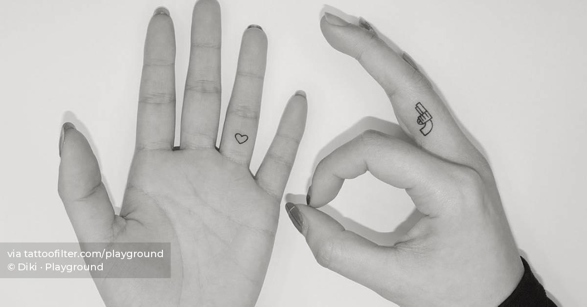 Little heart and revolver tattooed on the fingers.