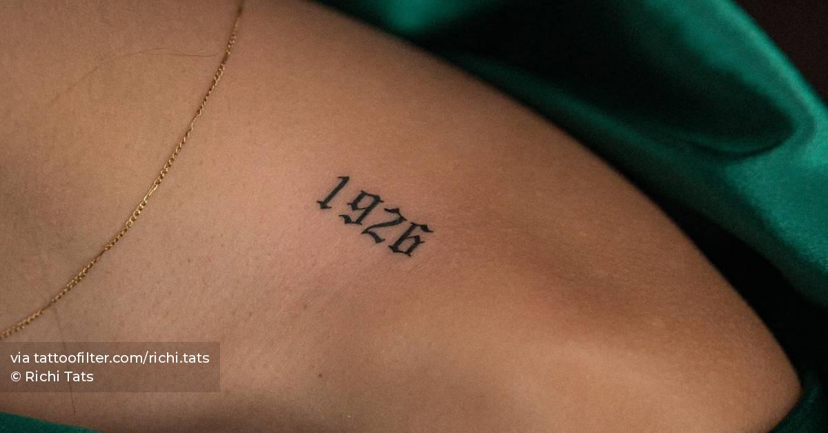 "1926" lettering tattoo placed on the top of shoulder.