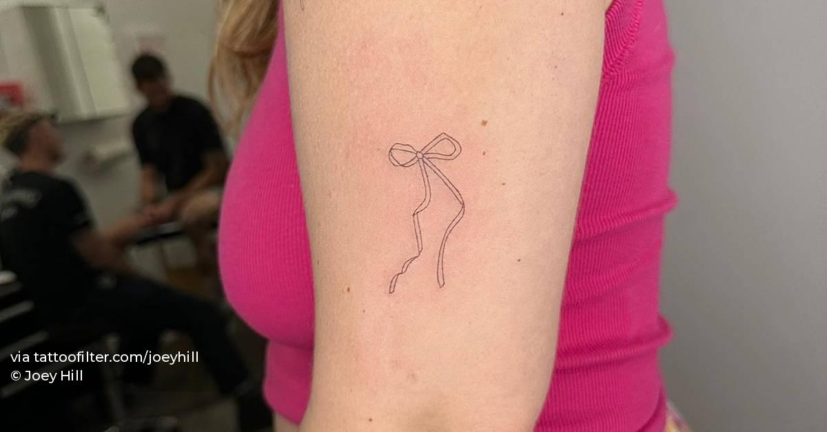 Ribbon tattoo located on the upper arm, fine line