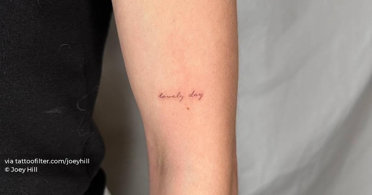 "Lovely day" lettering tattoo located on the upper arm.