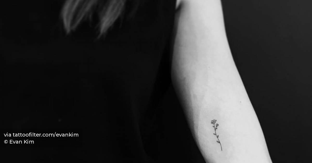 Minimalistic flower tattoo located on the inner arm.