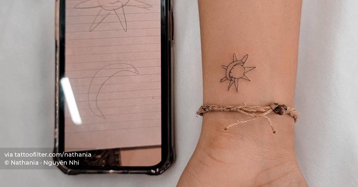 Fine line eclipse tattoo located on the wrist.