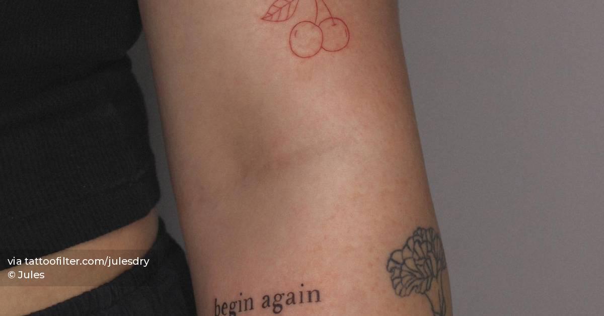 "Begin again" and red cherries tattooed on the arm.