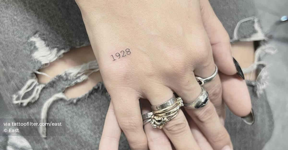 "1928" lettering tattoo located on the hand.