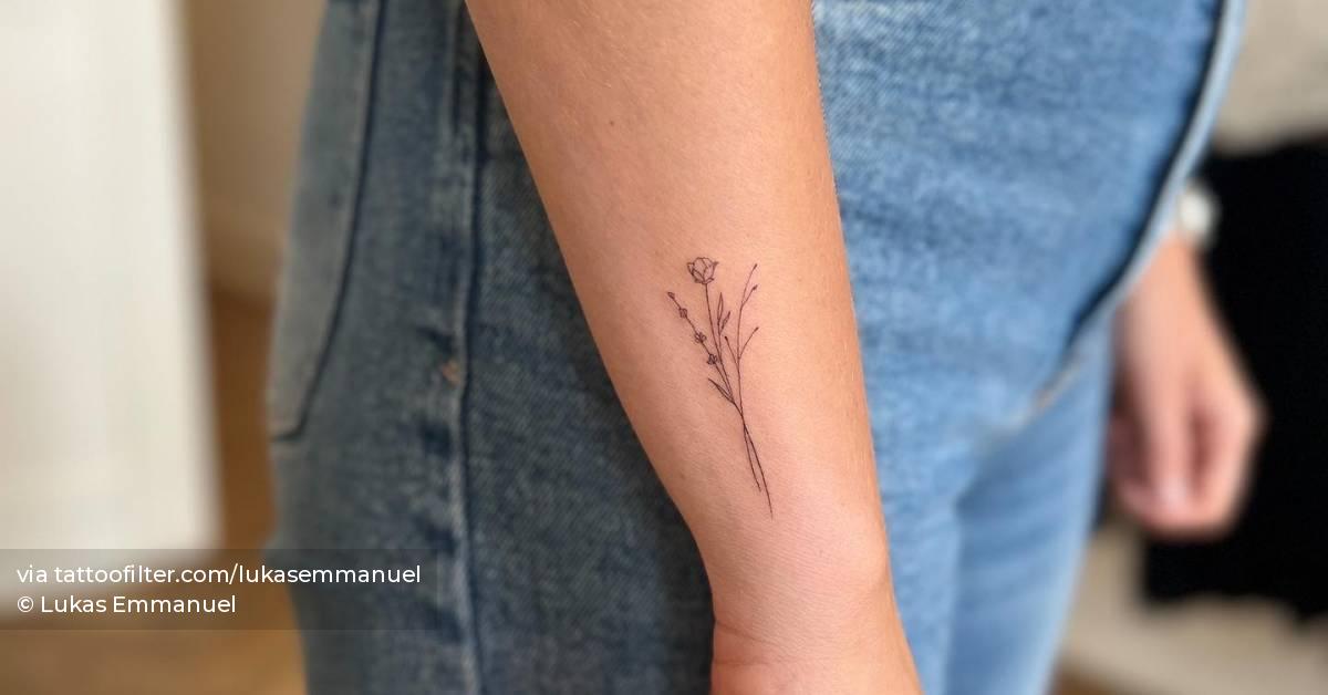 Fine line flower branch tattooed on the wrist.