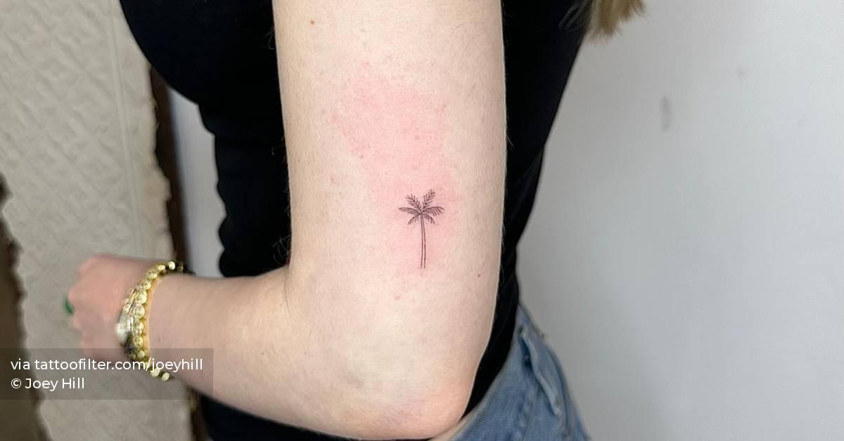 Little palm tree tattoo located on the upper arm.