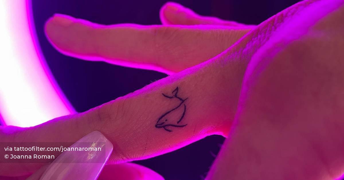 Super tiny dolphin tattoo located on the finger,
