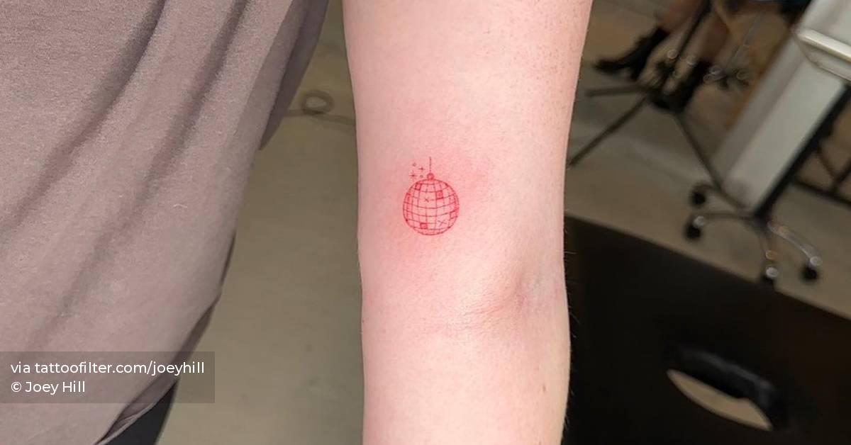 Red disco ball tattoo located on the inner arm.
